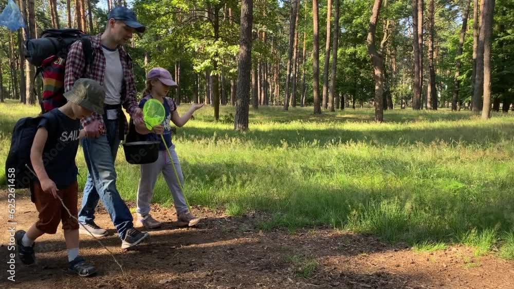 Pan shot father daughter son traverse trail carrying backpacks filled ...