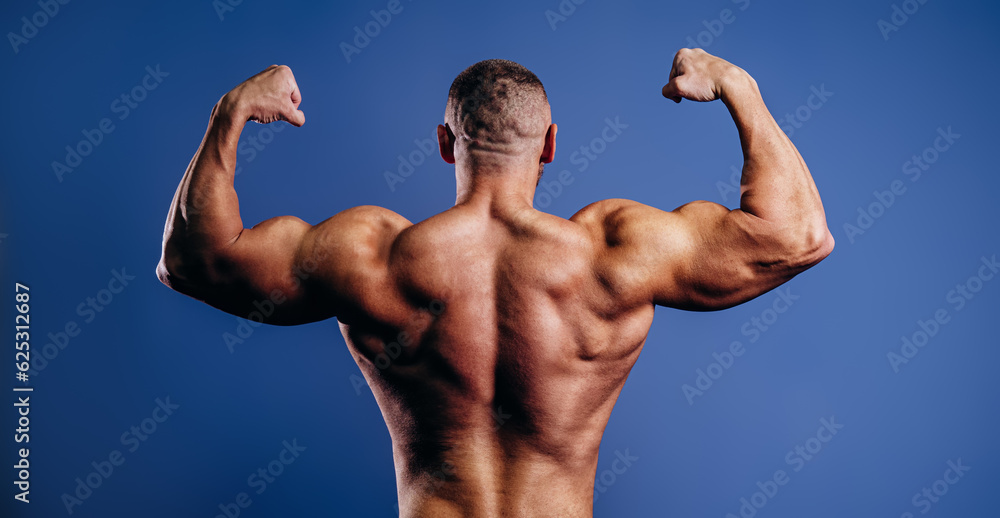 Male bodybuilder with bare torso shows muscularity against a blue ...