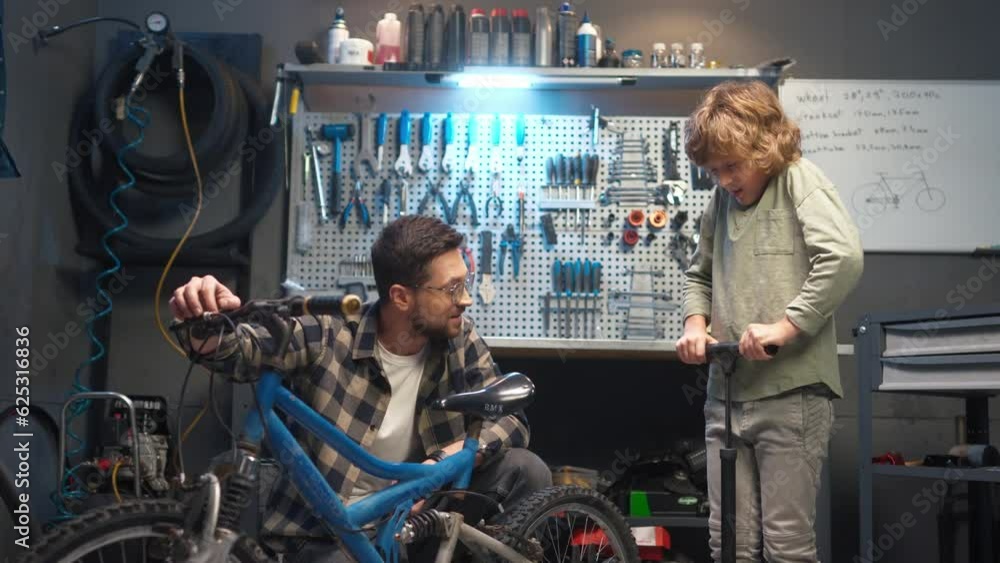 Father and son working in garage. Dad teaching son to repair bicycle ...