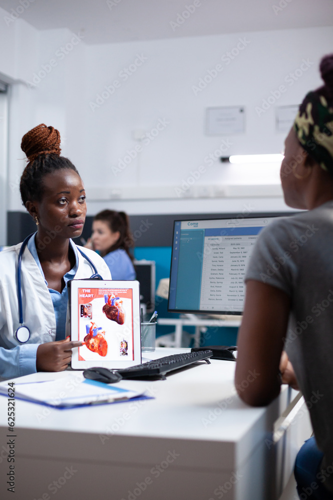 Cardiologist showing heart chart on tablet to patient during checkup ...