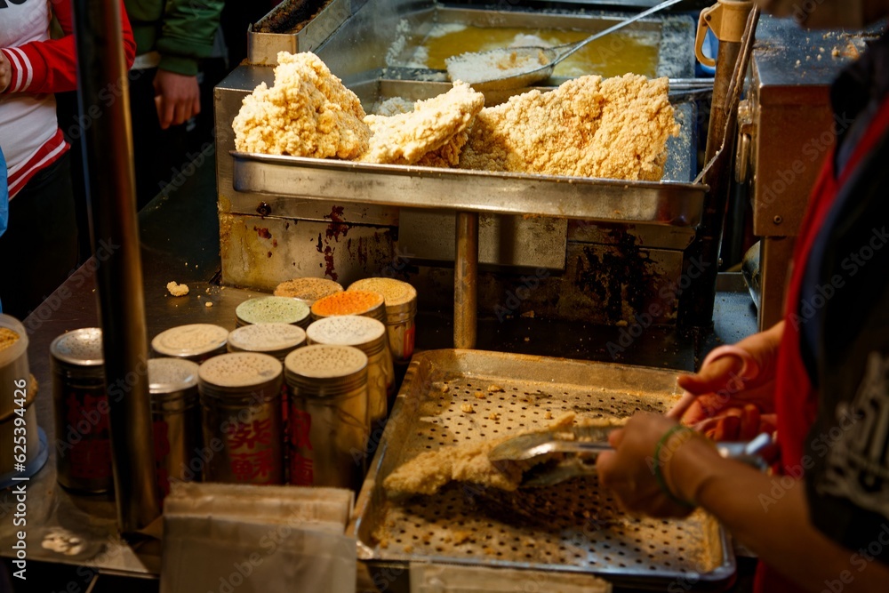 A stall vendor seasoning crispy deep-fried chicken cutlets with spice ...