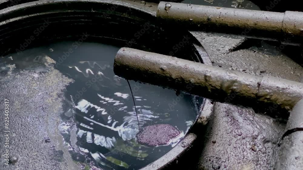 Black chemical wastewater pouring on the storage tank coming out from ...