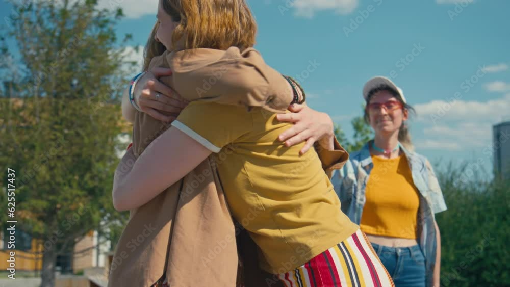 Tilt shot of Caucasian teenage girl helping female friend to stand up ...