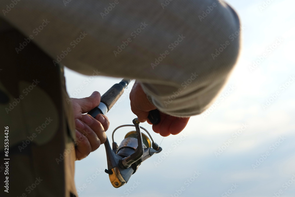 Old man fishing. Senior gray haired fisherman throws a spinning from ...