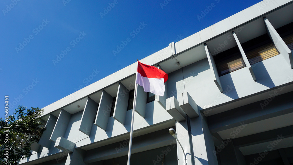 Indonesia flag fluttering on a pole in front of the gray building ...