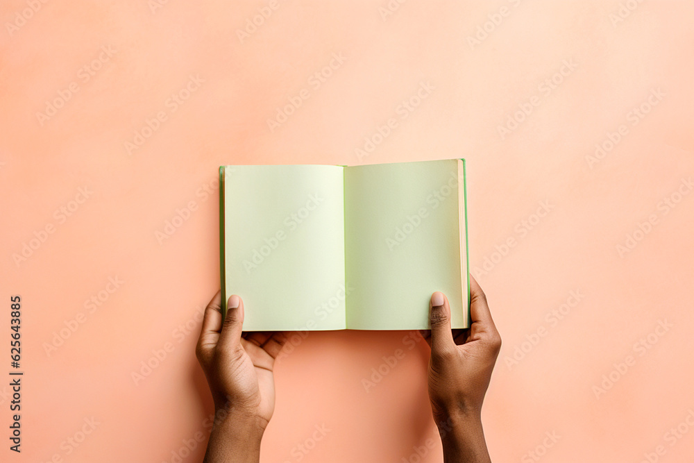 Hands holding an open book on pastel background. Reading, studying ...