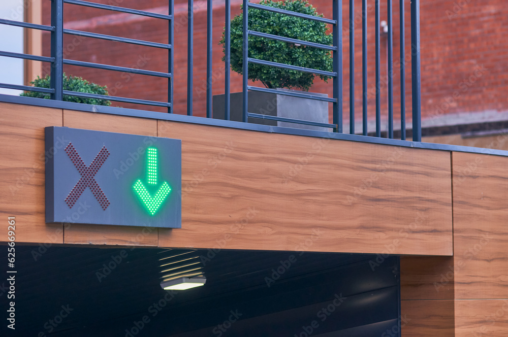 Green arrow down on the facade of a modern residential building close ...