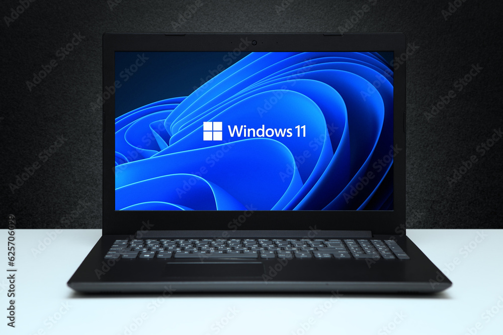 Windows 11 logo on the screen laptop computer black textured wall with ...