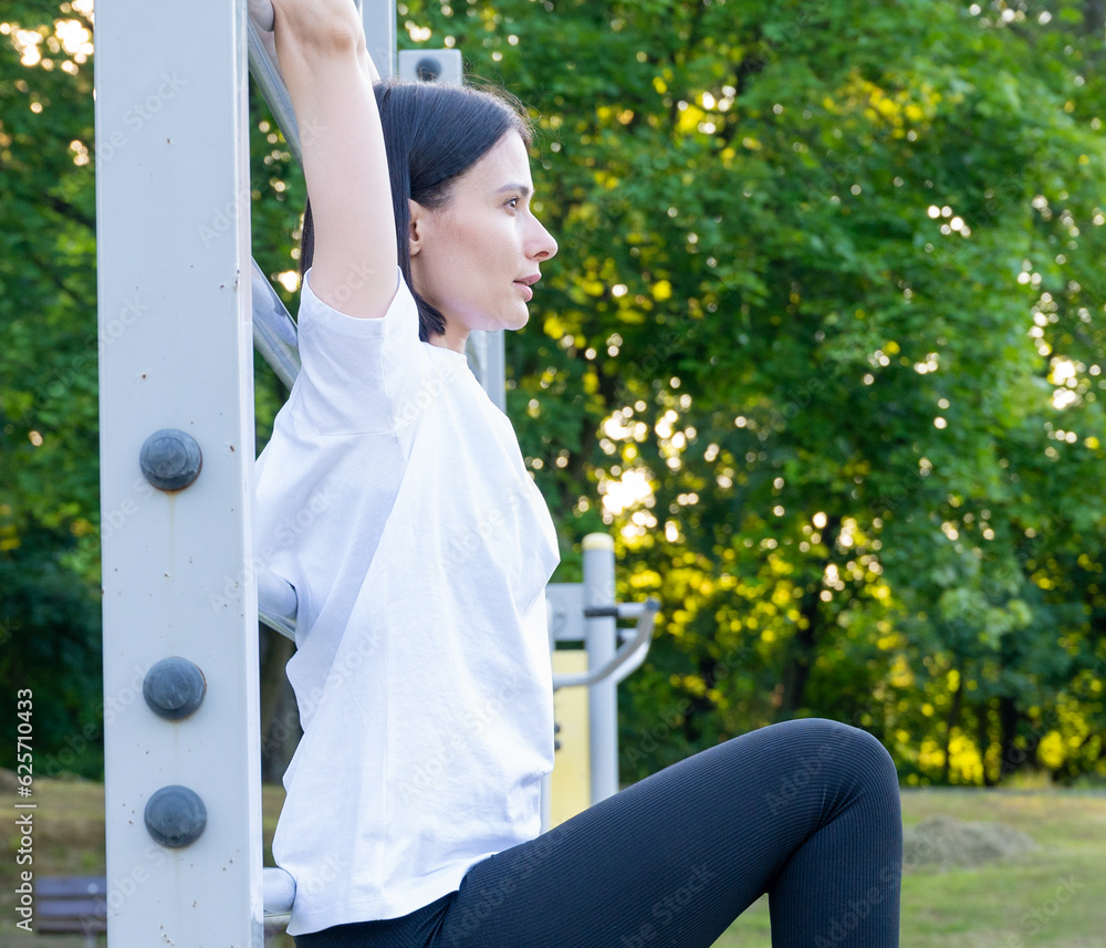 Woman doing belly press exercises on swedish wall. Girl in white t ...