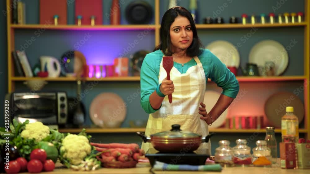 An Indian woman in the kitchen, ready to cook, wearing an angry ...