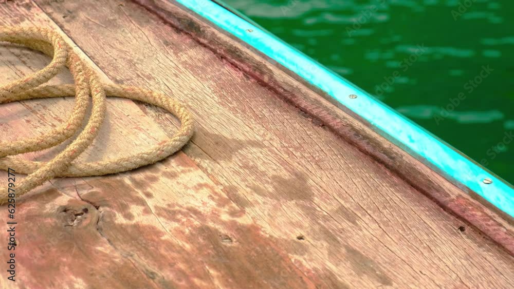 Motorboat rope lays on wooden plank in soft light on sunny day. Boat is ...