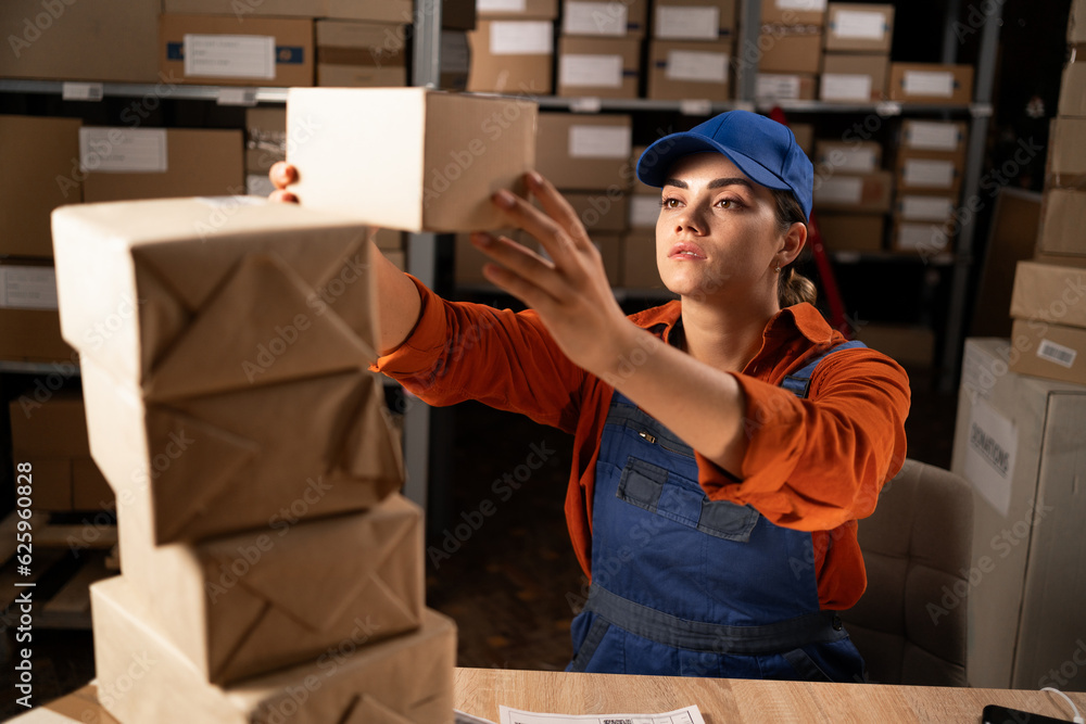 Woman working in a warehouse. Cardboard boxes standing on a warehouse ...