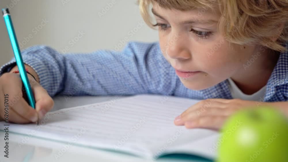 Elementary school student boy or girl writing letters, studying at desk ...