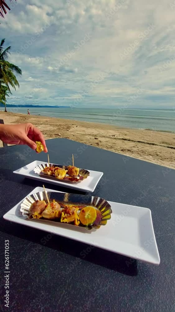 Vertical video of hand squeezing calamansi juice over pork siomai, a ...