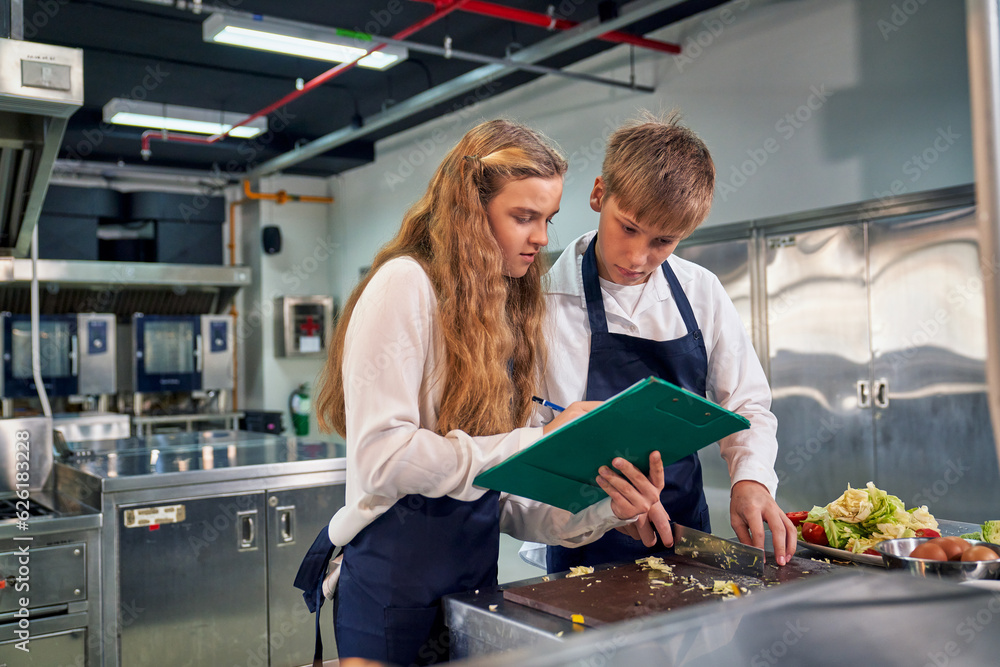 Two kids learning with lecture paper to cutting a vegetable in real ...