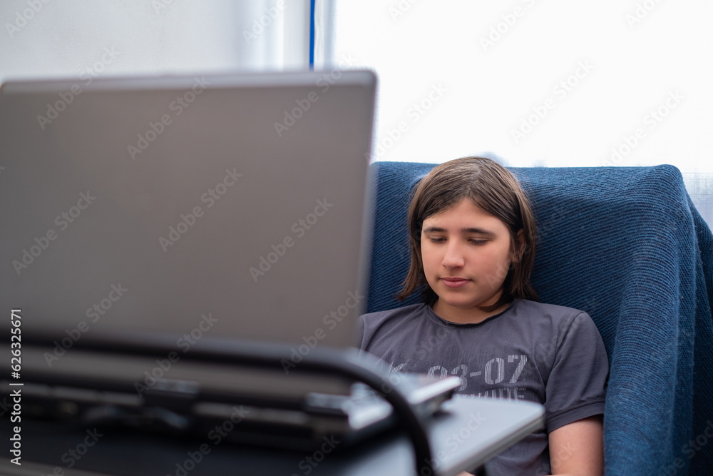 Teen boy study or play game on laptop home interior background ...