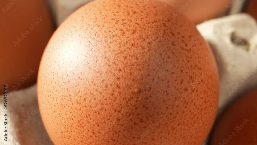 Macro video, fresh eggs are showcased, nestled in a paper tray, their ...