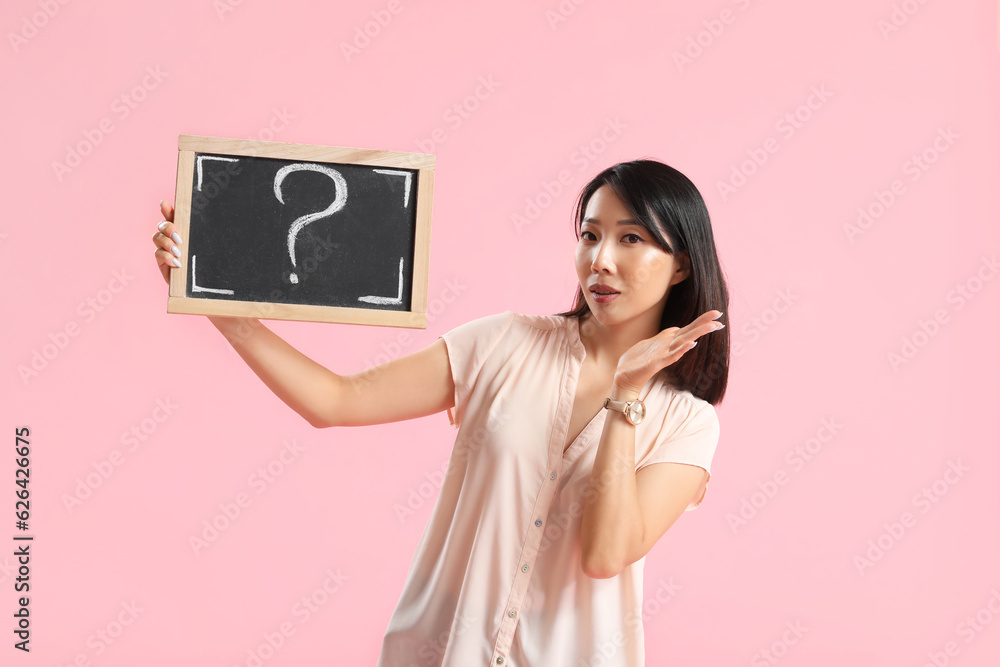Female Asian teacher holding chalkboard with question mark on pink ...