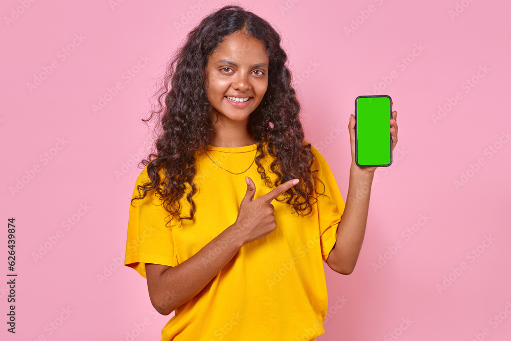Young satisfied Indian woman teenager with mobile phone points finger ...
