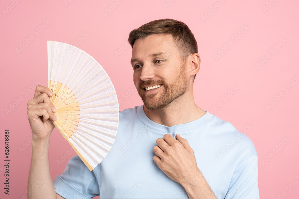 Relaxed smiling man using paper fan at summer hot weather, sweating ...