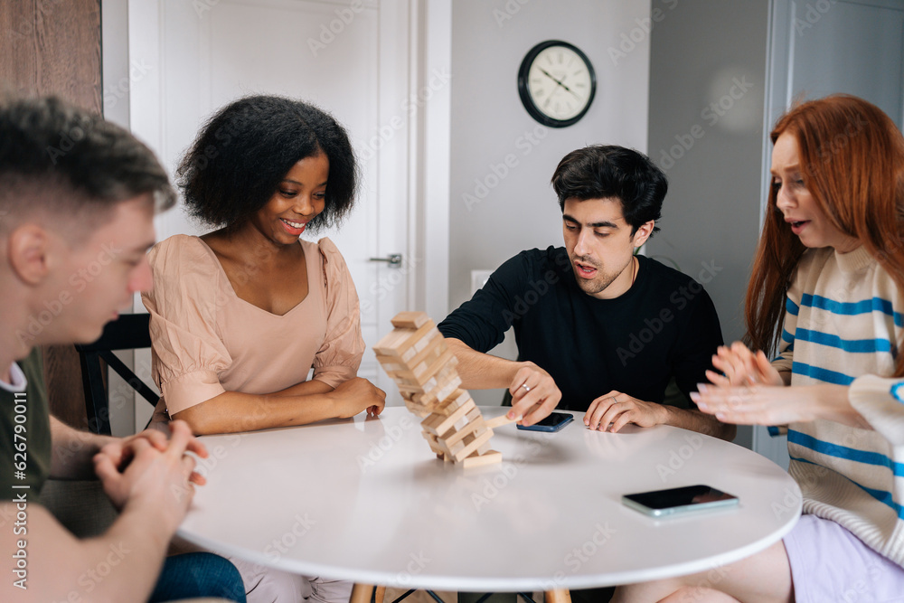 Multiethnic happy friends playing crash and stack board game, catching ...