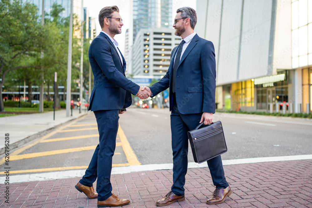Businessmen in suit shaking hands outdoors. Handshake between two ...