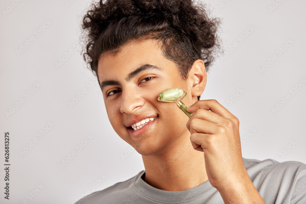 Young handsome smiling guy using jade de-puffing face roller to keep ...