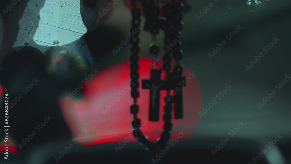 Christian cross on display at car windshield while raining in ...