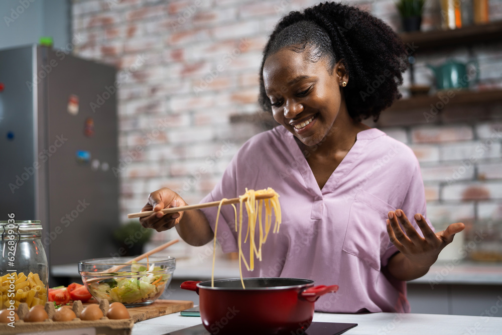 Young woman in kitchen. Beautiful African woman cooking pasta.. Stock ...