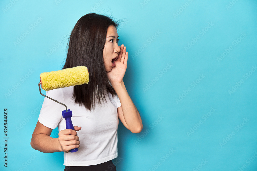Young Asian woman with paint roller, DIY concept, shouting and holding ...