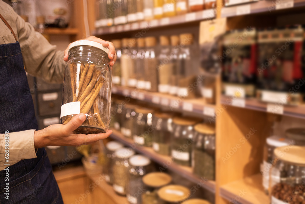 Crop male seller putting jars with assorted products on shelf Stock ...