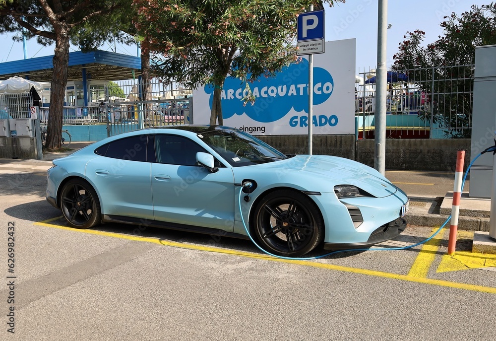 Grado, Italy. July 23, 2023. Blue Porsche Taycan Turbo on charging at ...