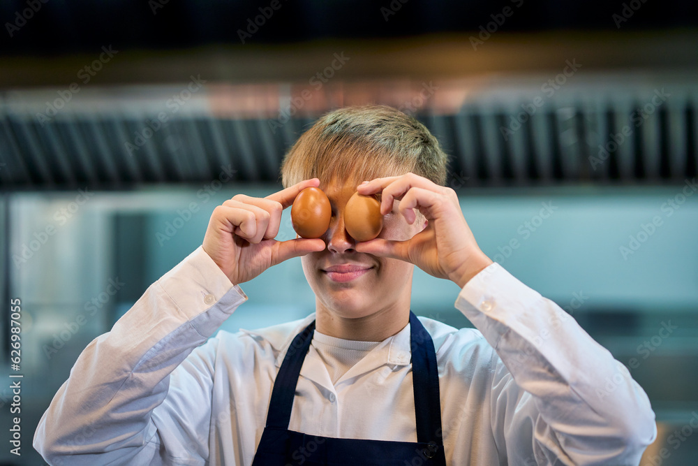 Funny scene with single boy with chef uniform and two eggs on his eye ...