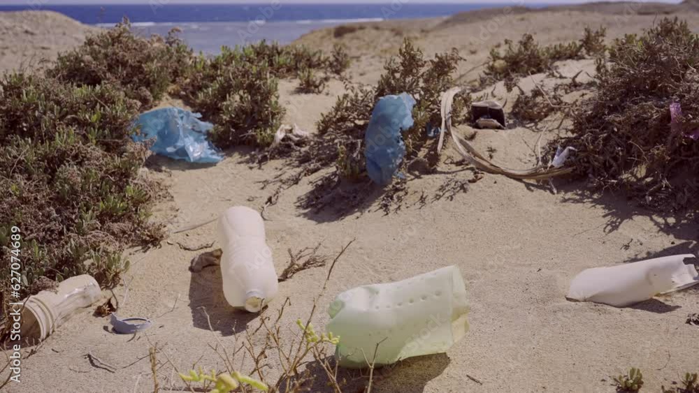 Plastic pollute of sandy desert with se in background, Closeup, Camer ...
