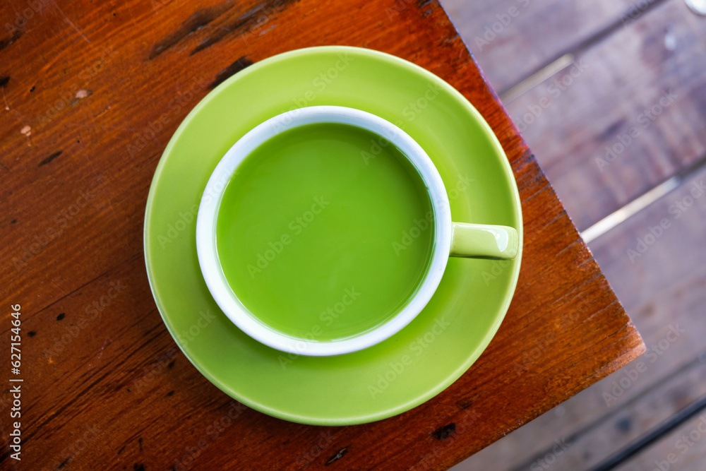 a cup of hot milk green tea on the table, top view. adding milk to ...
