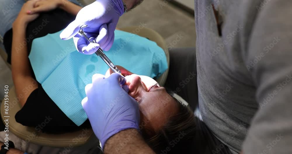Dentist makes local anesthesia before operation. Dentist installs ...