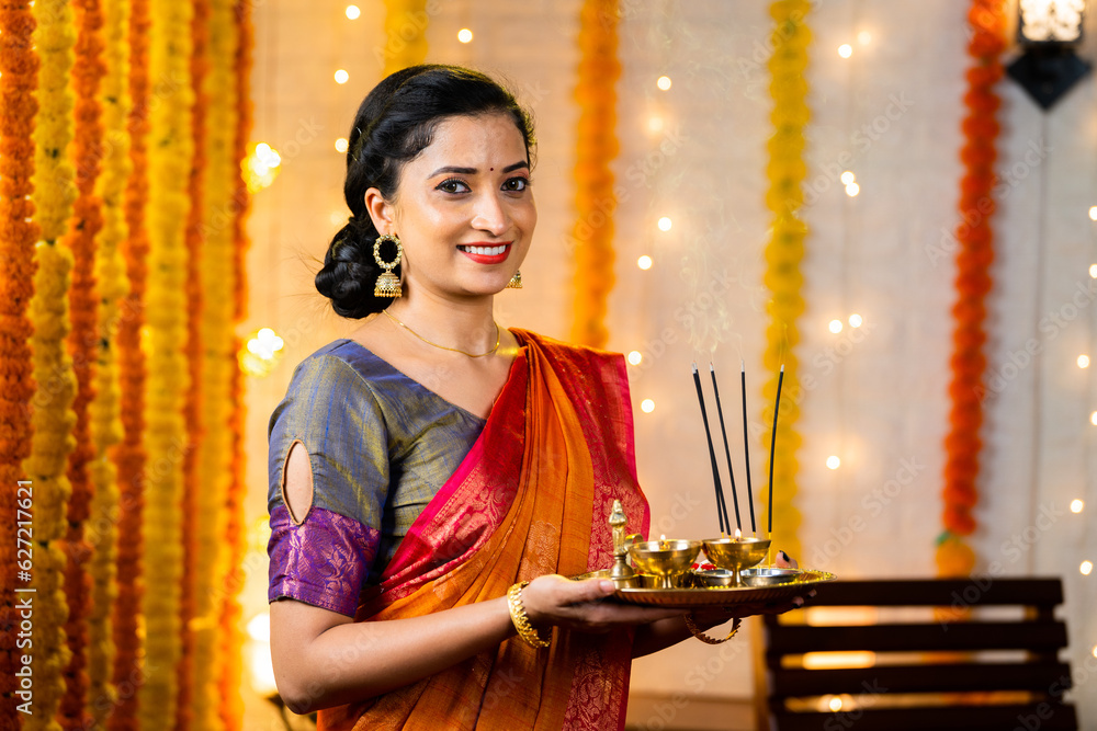 Happy indian girl in traditional ethnic wear holding pooja plate with ...