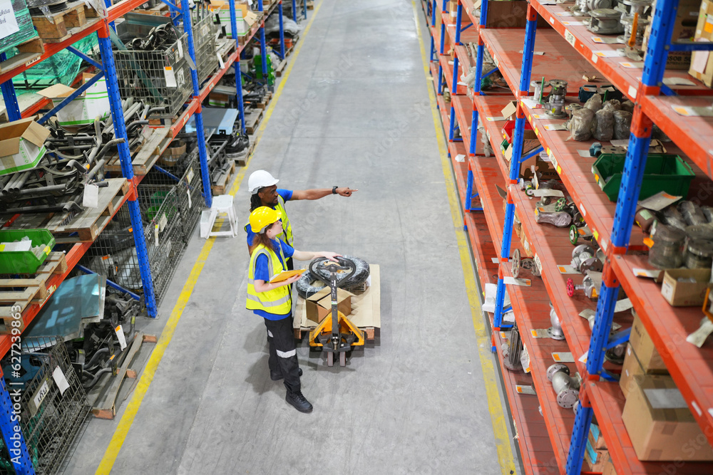Worker working in large warehouse holding paper chart check list ...