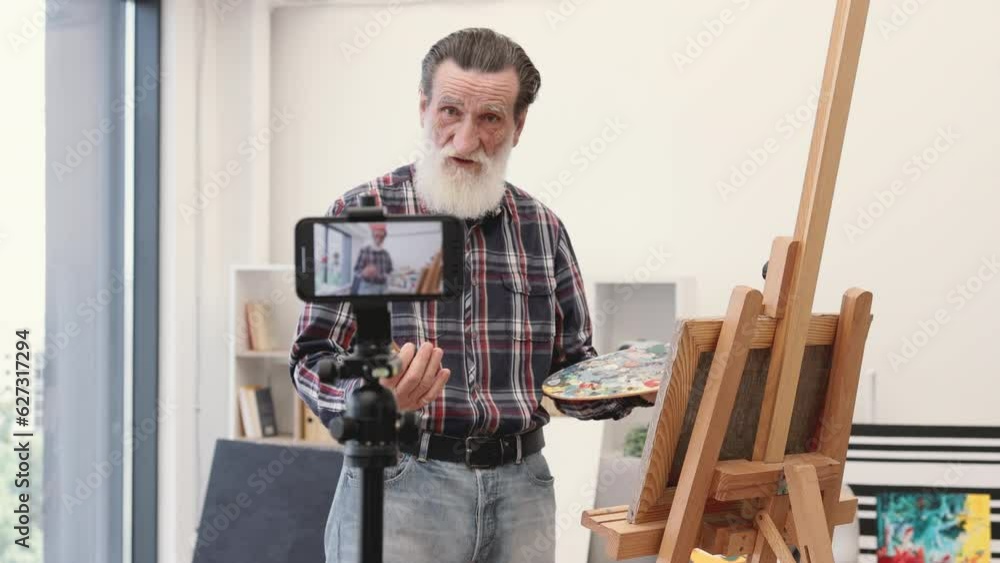 Aged gentleman with long grey beard standing in front of tripod with ...