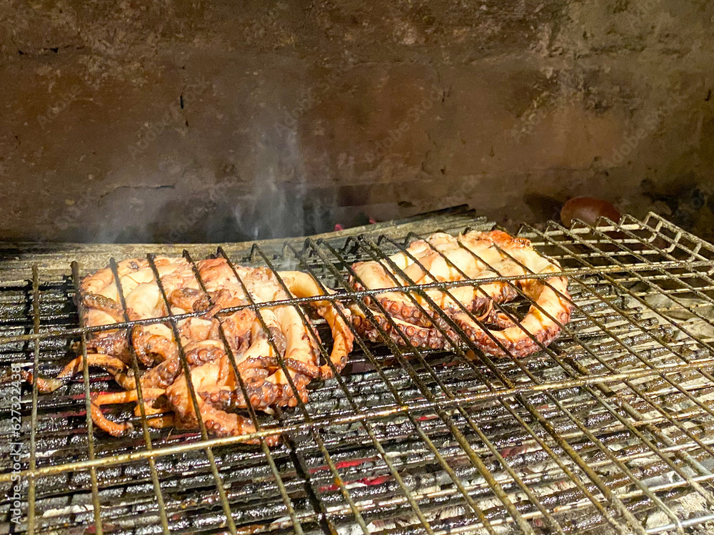 Octopuses fresh out of the Aegean Sea are cooked on the grill fire ...