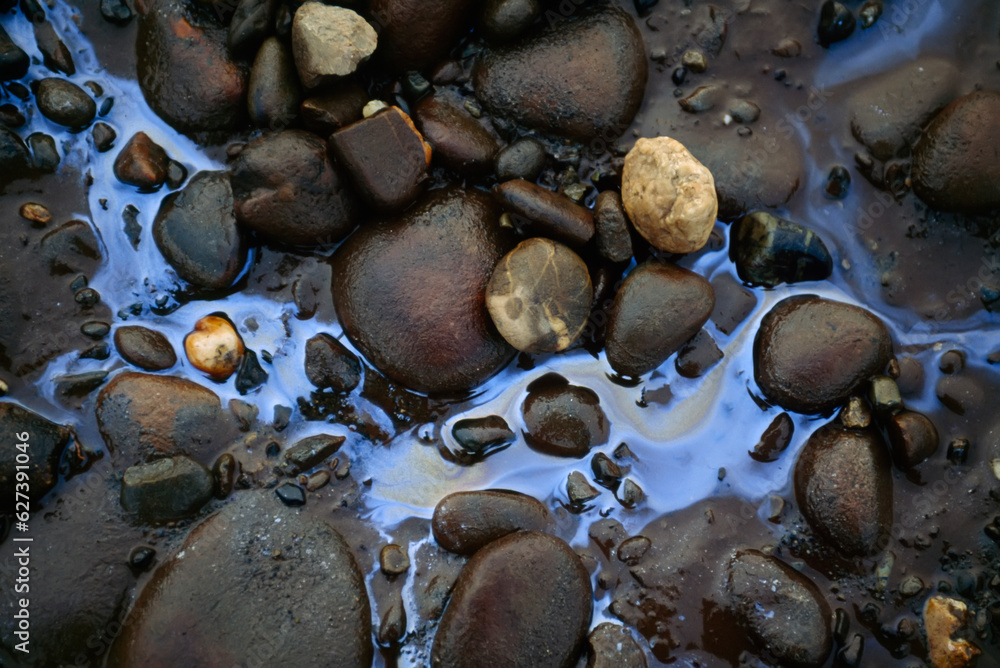 Oil slick and pebbles in a stream; North Slope, Alaska, United States ...