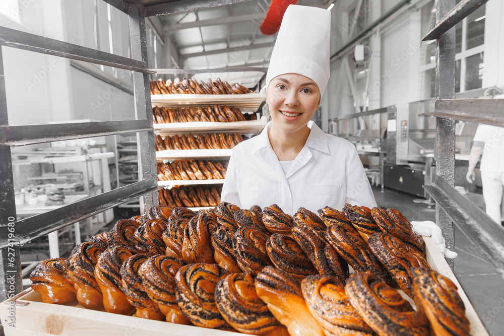 Happy worker woman baker in chef uniform hold freshly bakery poppy seed ...