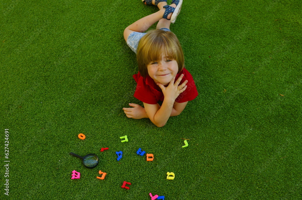 Hebrew alphabet. The boy is learning Hebrew. Multi-colored letters on ...