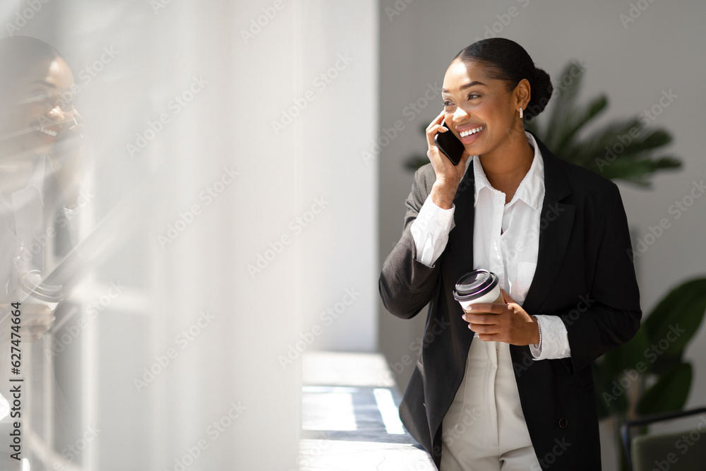 Happy black woman in suit having phone conversation and drinking coffee ...