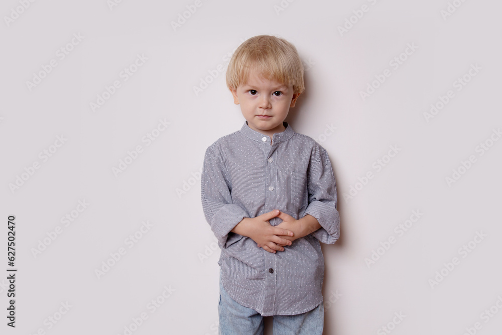 little fair-haired boy in a plaid shirt holding his stomach, stomach ...