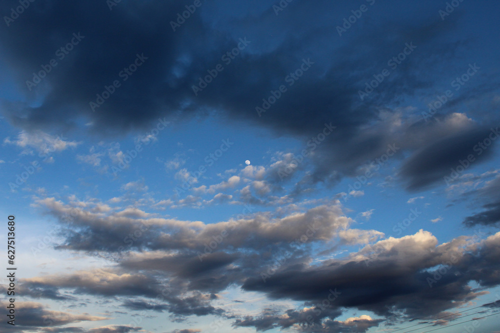 Cielo azul contrastado con nubes negras, blancas y grises con luna ...