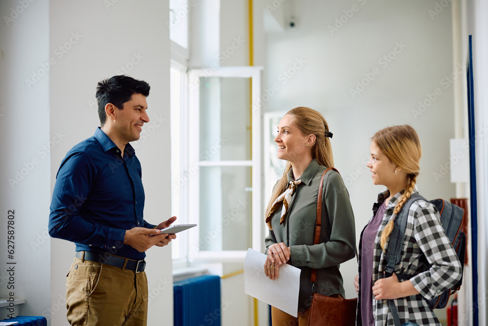 Happy mother and her teenage daughter communicating with principal in ...