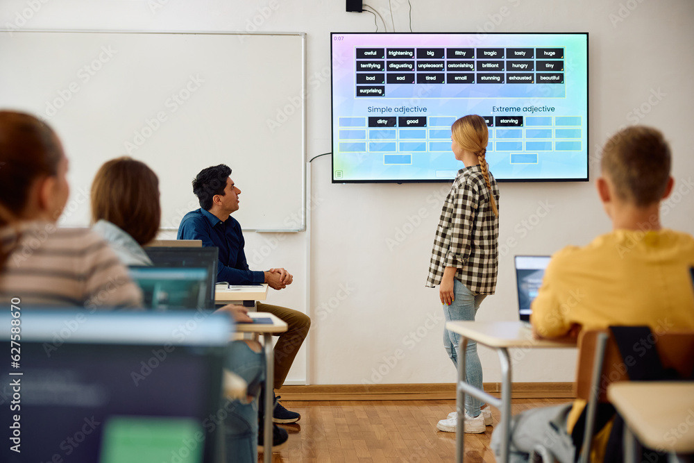 Male teacher and his students using interactive whiteboard during class ...
