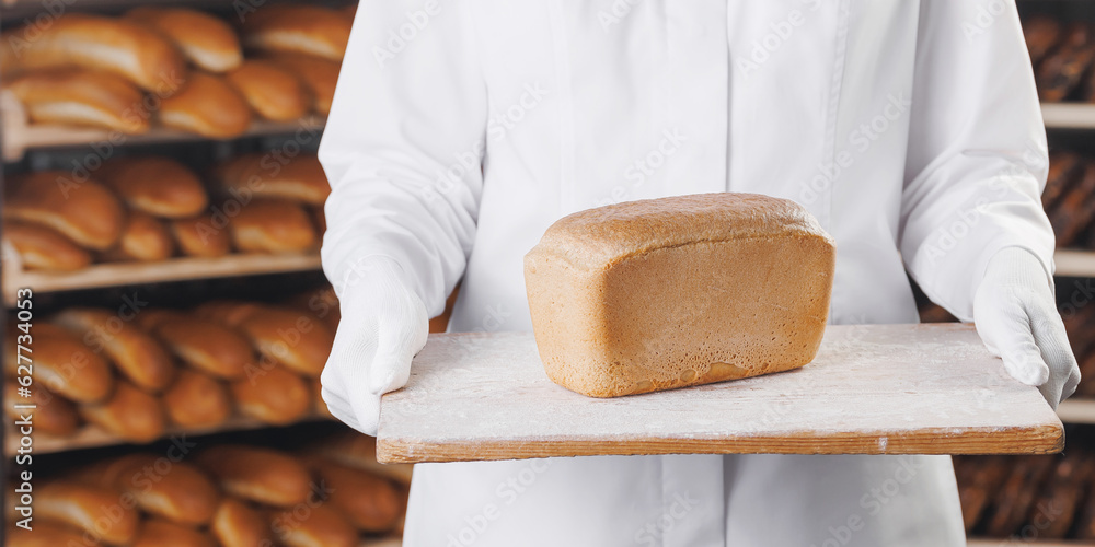 Young woman baker in chef uniform holding freshly craft baked bread ...