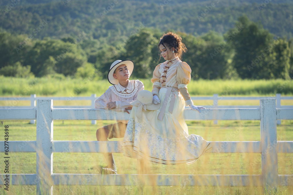 Teenage boys and girls in ancient-style costumes sitting on white fence ...
